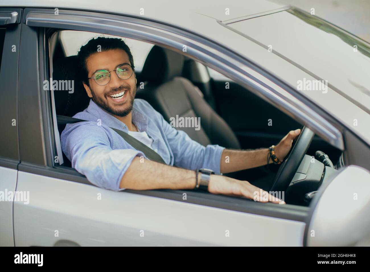 Cheerful arab guy driving right wheel car Stock Photo - Alamy