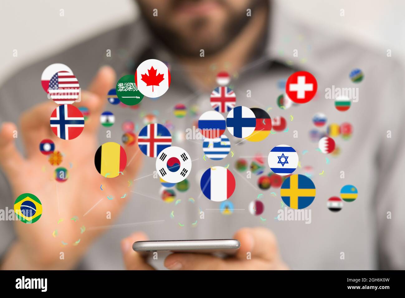 A hand holding icons of various flags over the smartphone - the concept ...