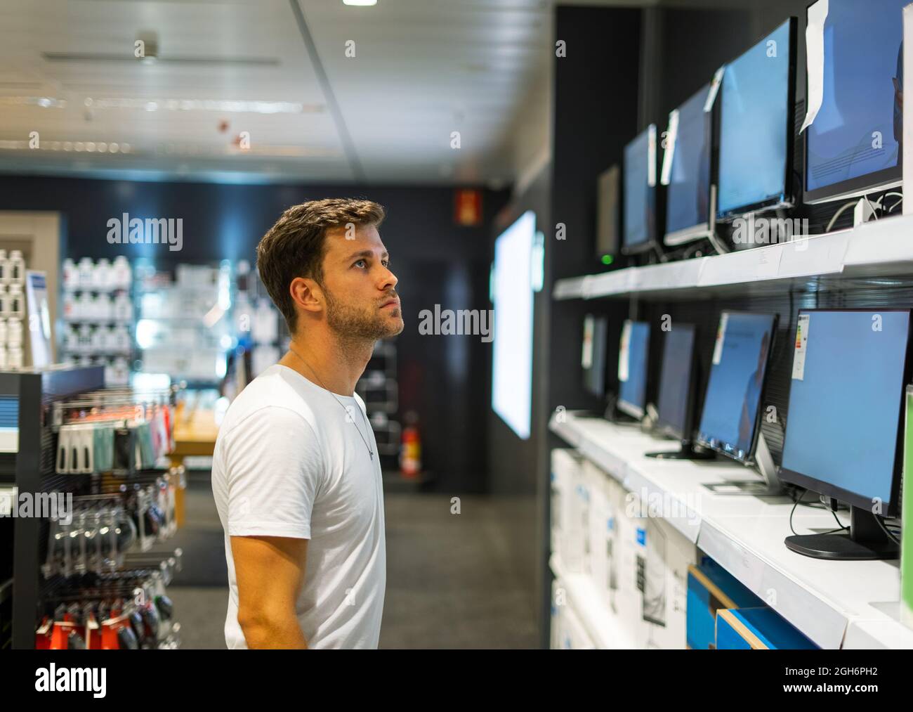 Side view of concentrated male buyer picking computer monitor while ...