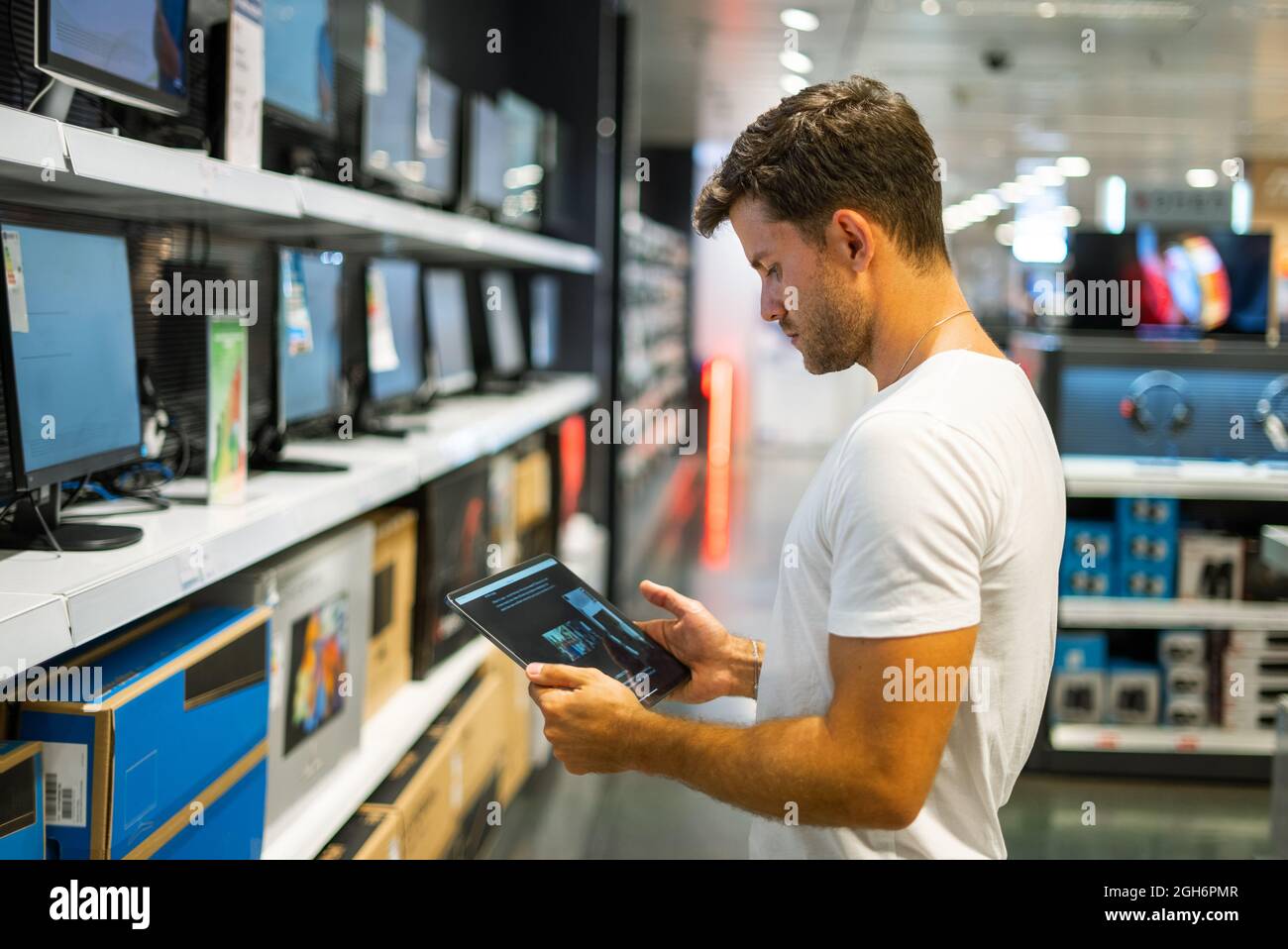 Side view of male customer using tablet while standing in store and ...