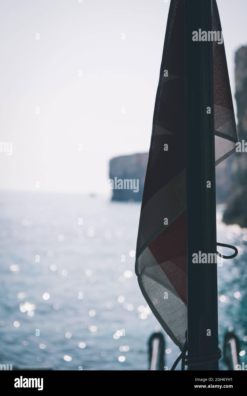 COMINO, MALTA - Aug 08, 2021: A vertical shot of the Maltese flag flies ...