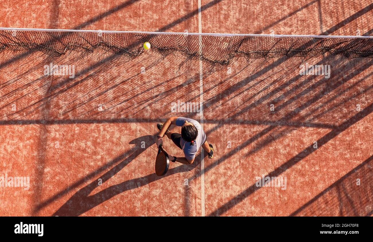 Overhead of a paddle tennis player hitting the ball near the net on an ...