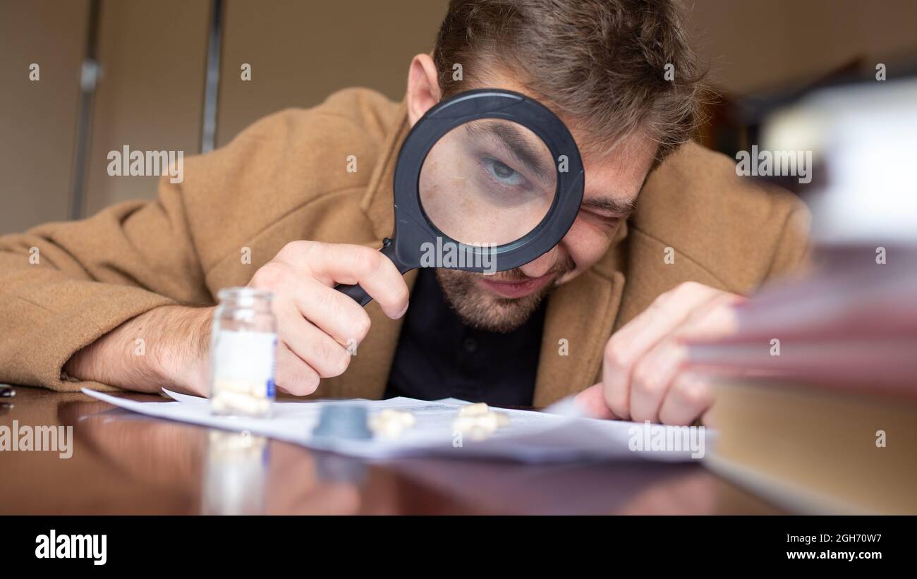 A detective examining evidence with a magnifying glass Stock Photo - Alamy