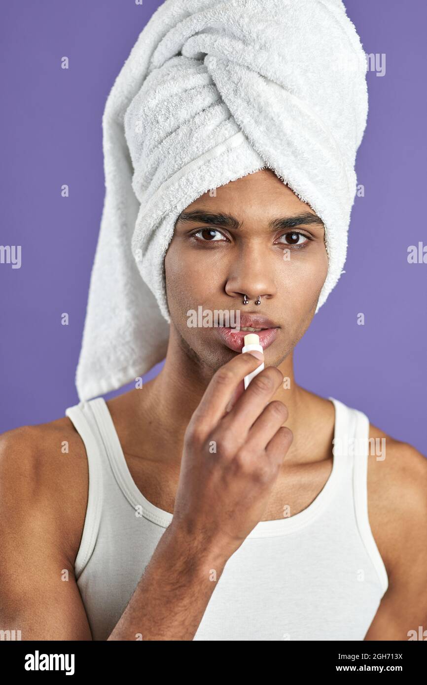 Transgender young man use lips balm and looking camera portrait ...