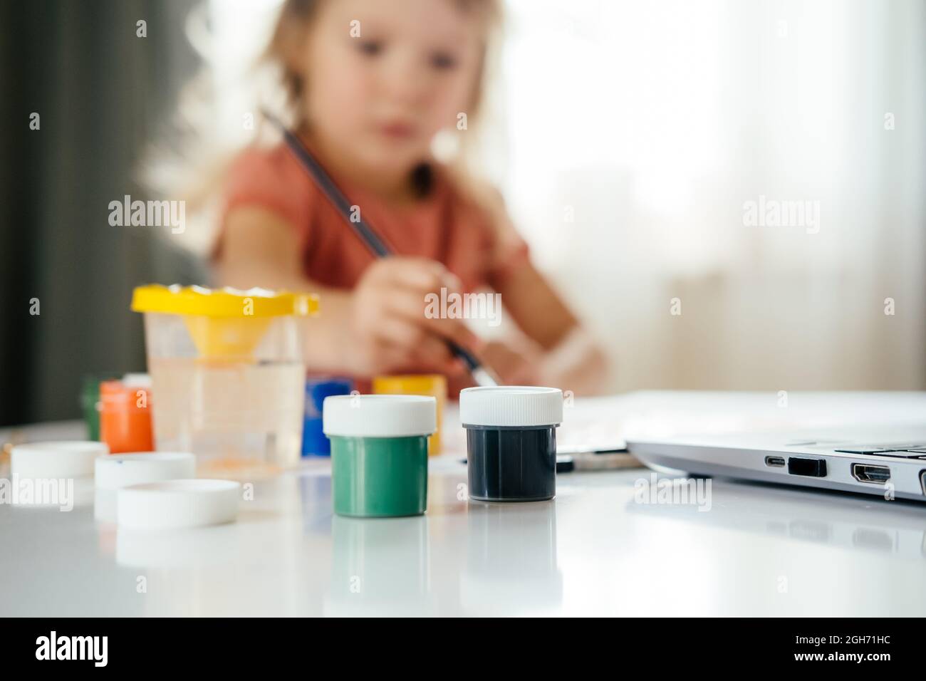 Young cute girl spending a time drawing using online lessons on laptop ...