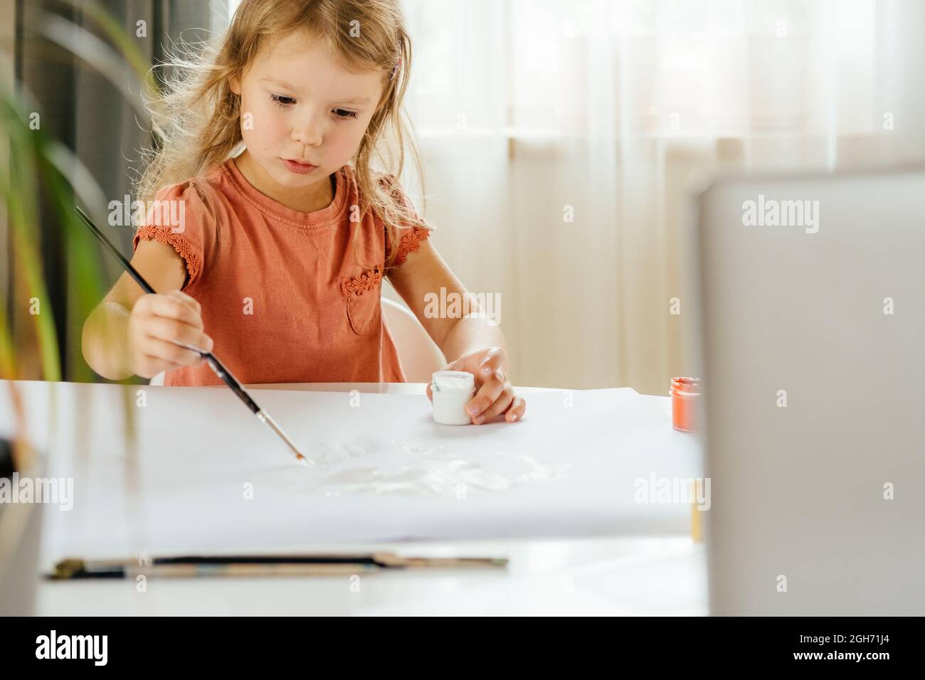 Young cute girl spending a time drawing using online lessons on laptop ...
