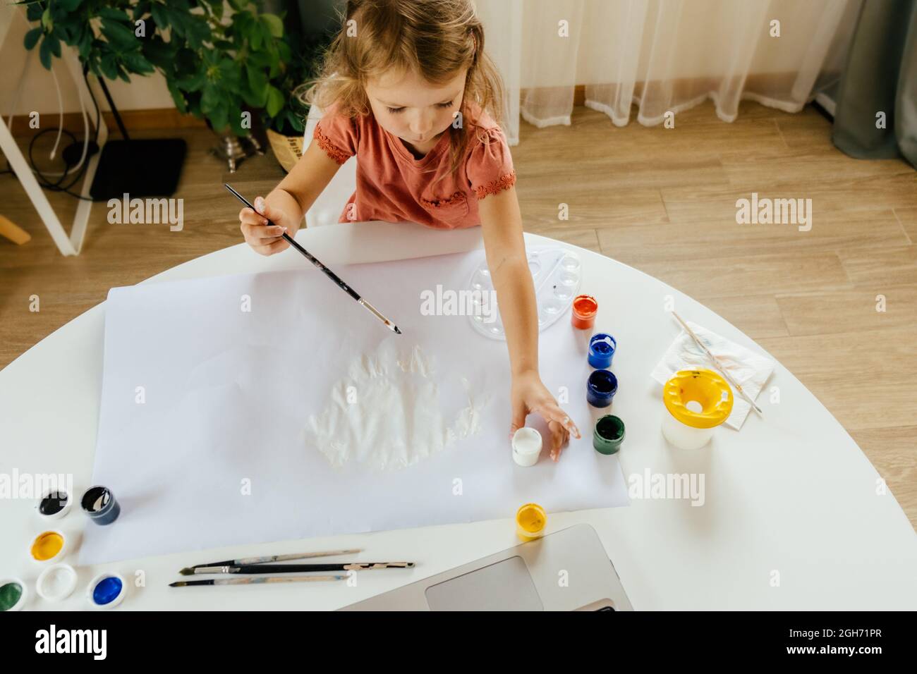 Young cute girl spending a time drawing using online lessons on laptop ...
