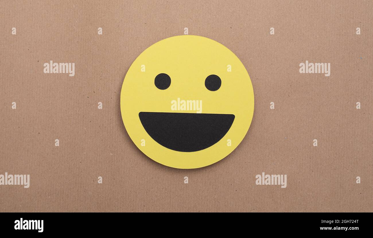A yellow smiley emoji on a brown background, positive emotion concept ...