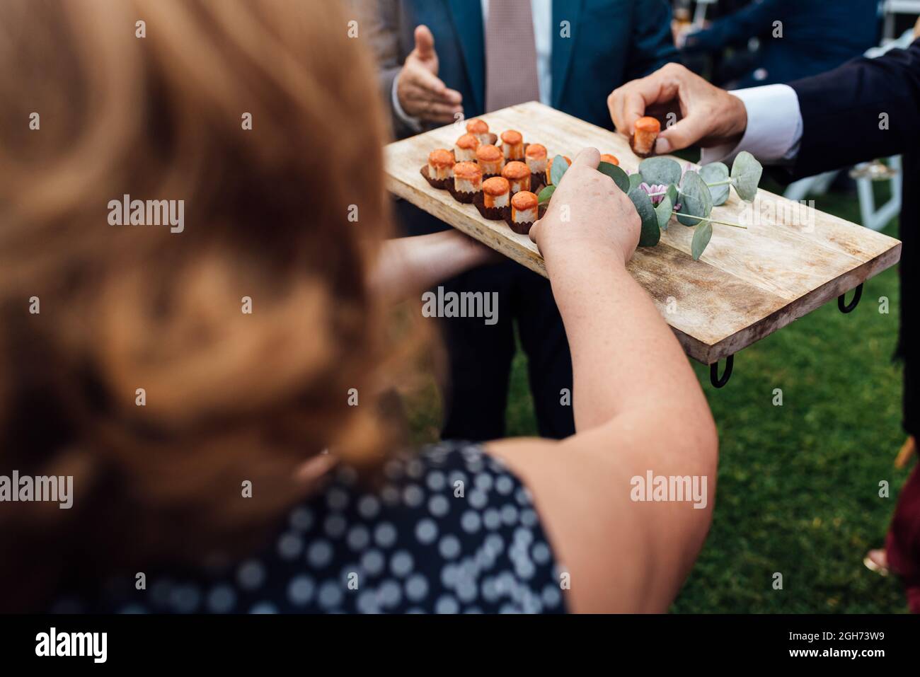 People taking snacks from the waiter during a party Stock Photo - Alamy