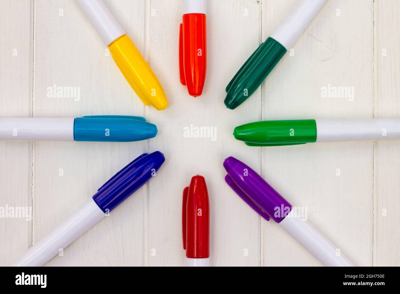 Multi-colored markers on a white wooden background. Top view. Copy ...