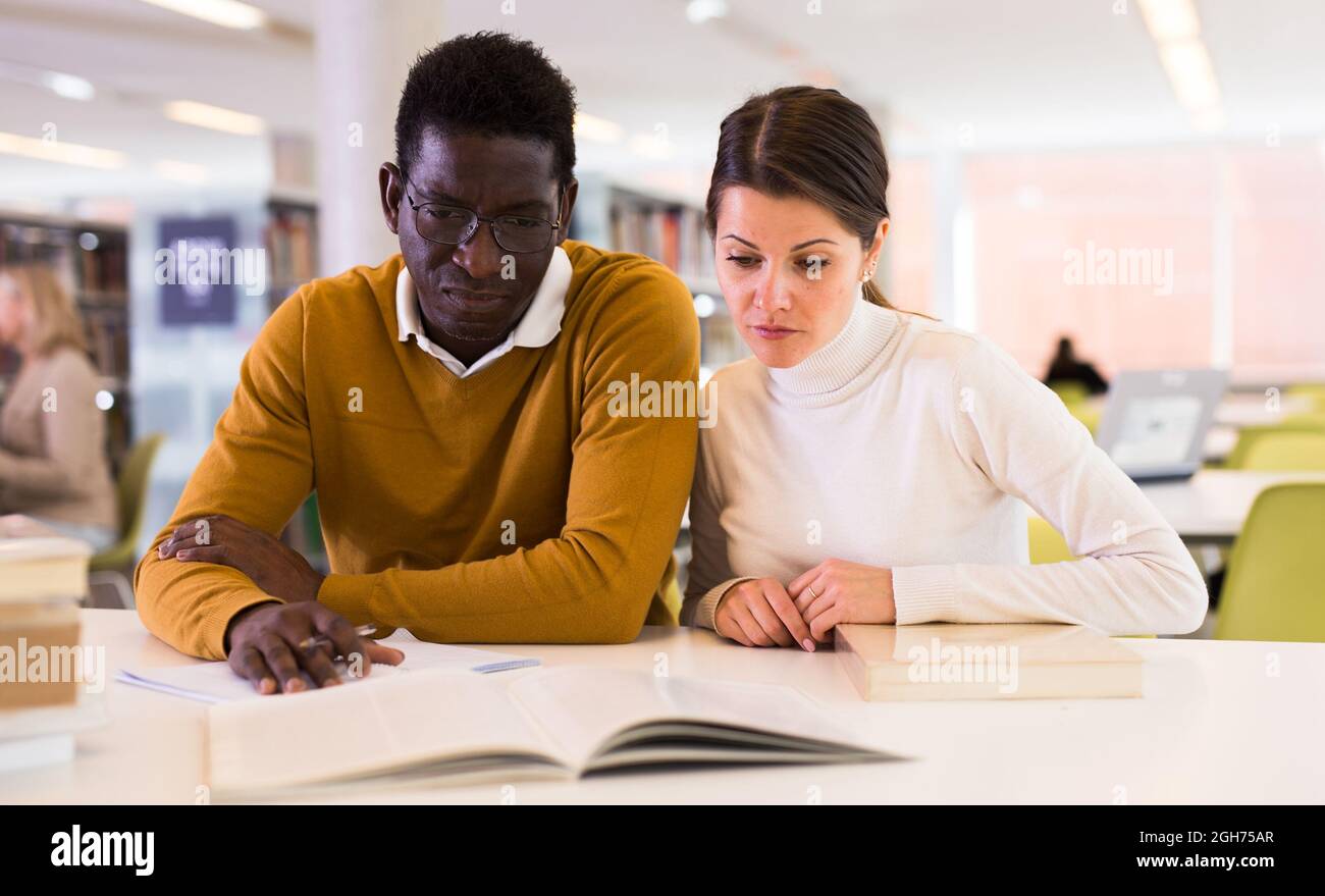 Portrait of couple of adult students studying together in public ...