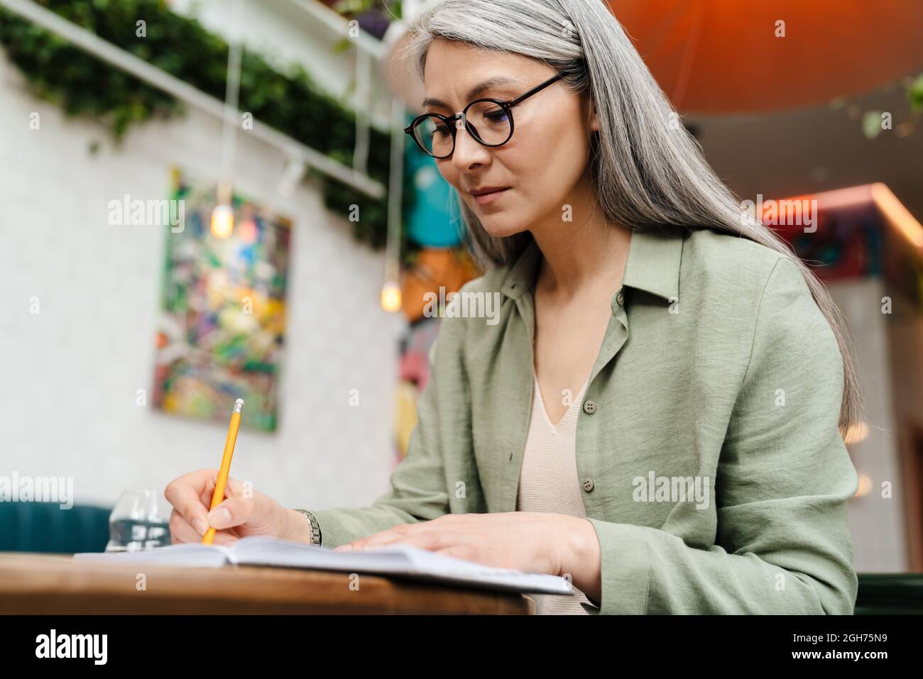 Mature grey woman writing down notes in planner at cafe indoors Stock ...