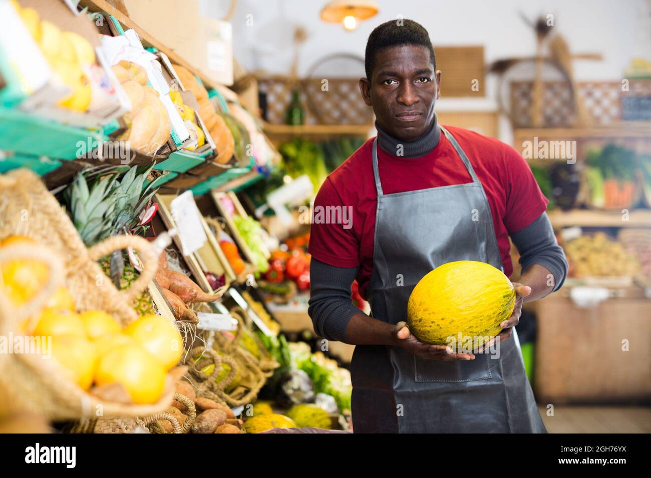 Fruit shop seller offering melon Stock Photo - Alamy