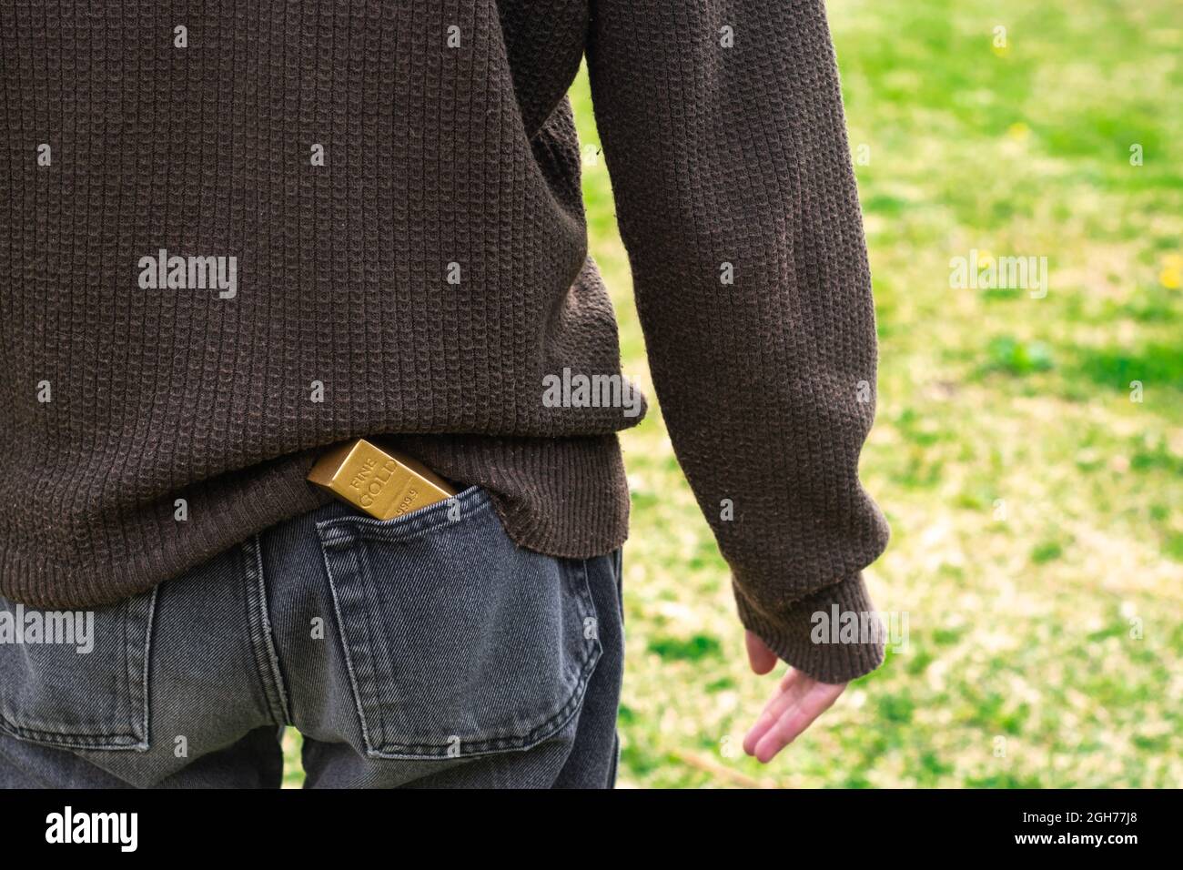 Partial view of a person with small gold ingot in their back pocket ...