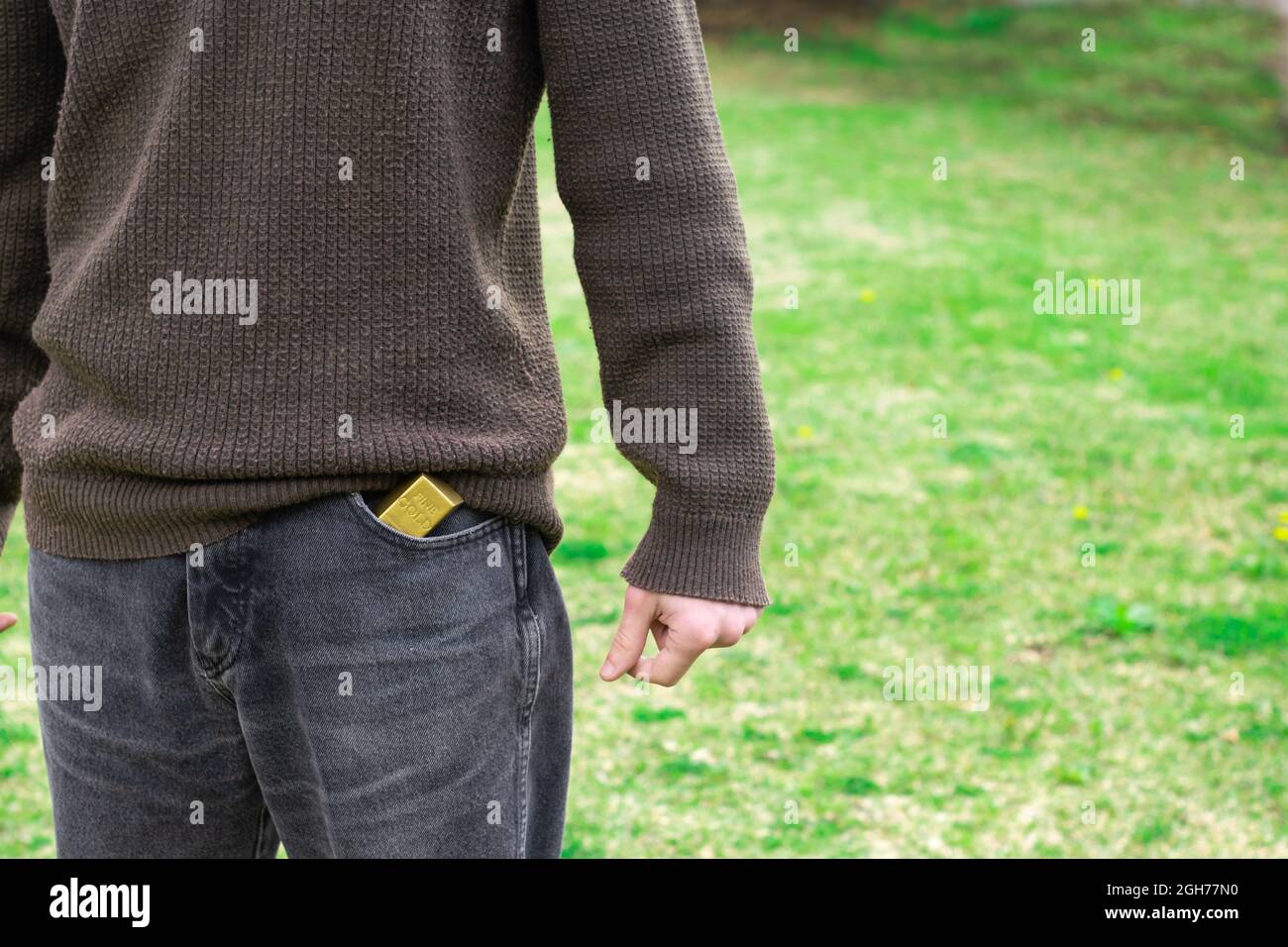 Partial view of person with small gold ingot in their front pocket ...