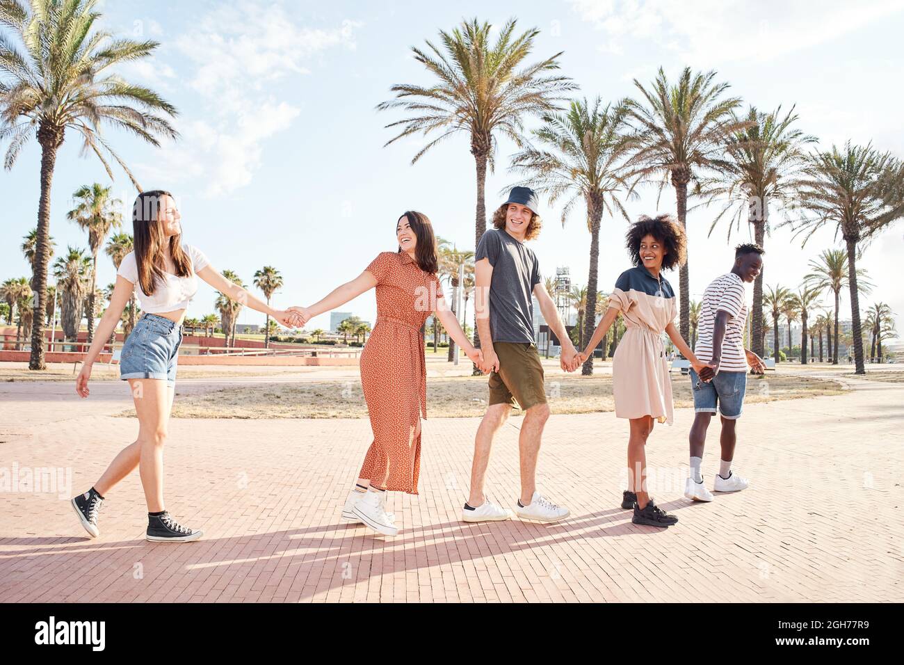 Young people of mixed races walk hand in hand through a city. Concept ...