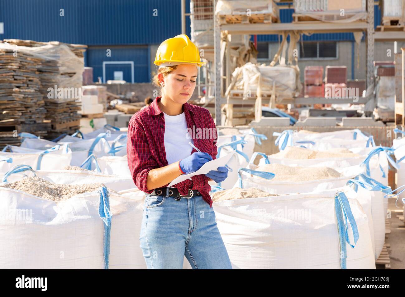 Attentive young female manager keeps records of bulk construction ...