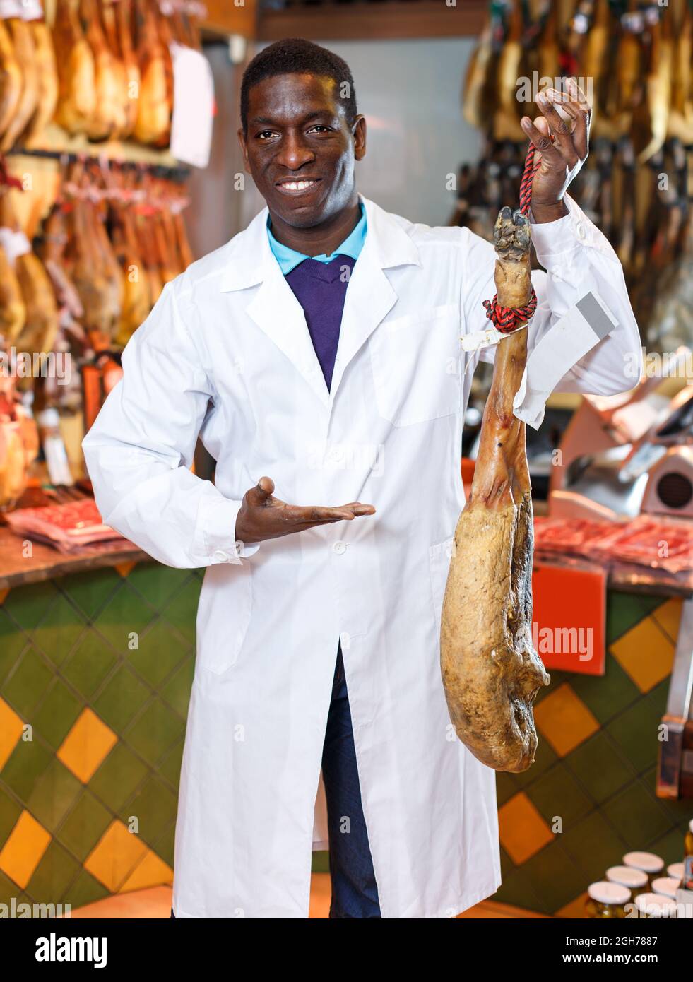 Positive owner of butcher shop selling jamon Stock Photo - Alamy