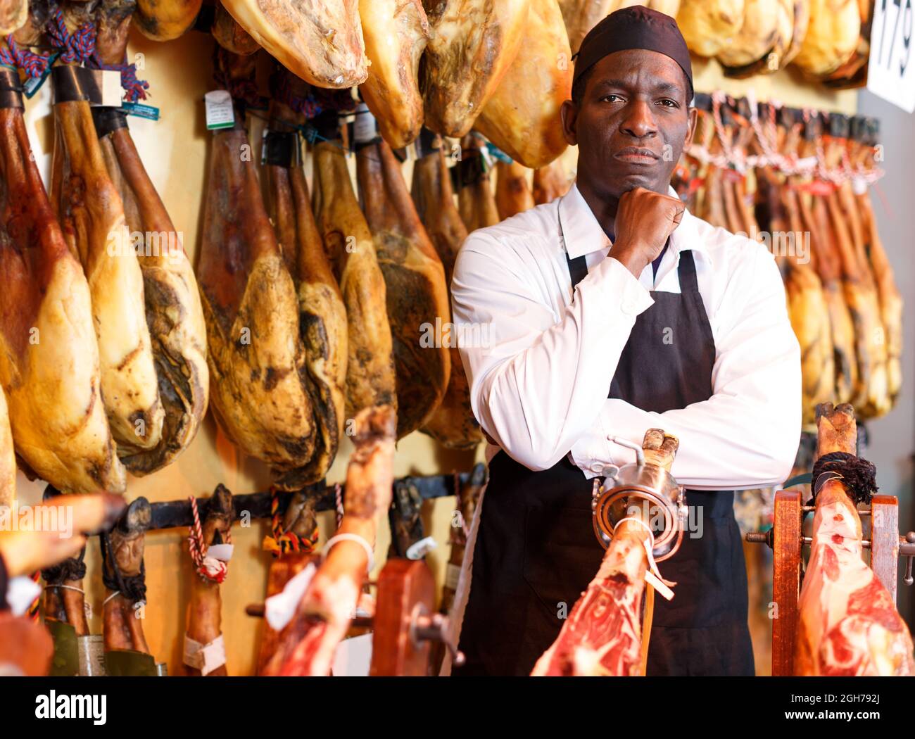 Butcher posing near ham counter Stock Photo - Alamy