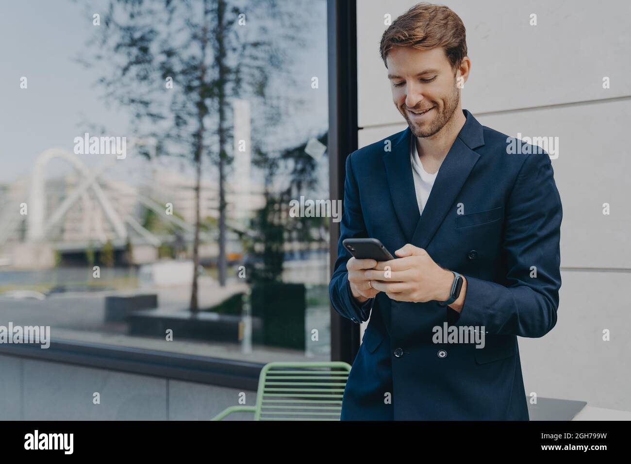 Pleased handsome male CEO or director holds mobile phone waits for call ...