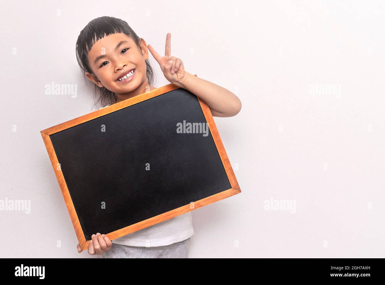 Asian child girl holding blank blackboard or chalkboard and show two ...
