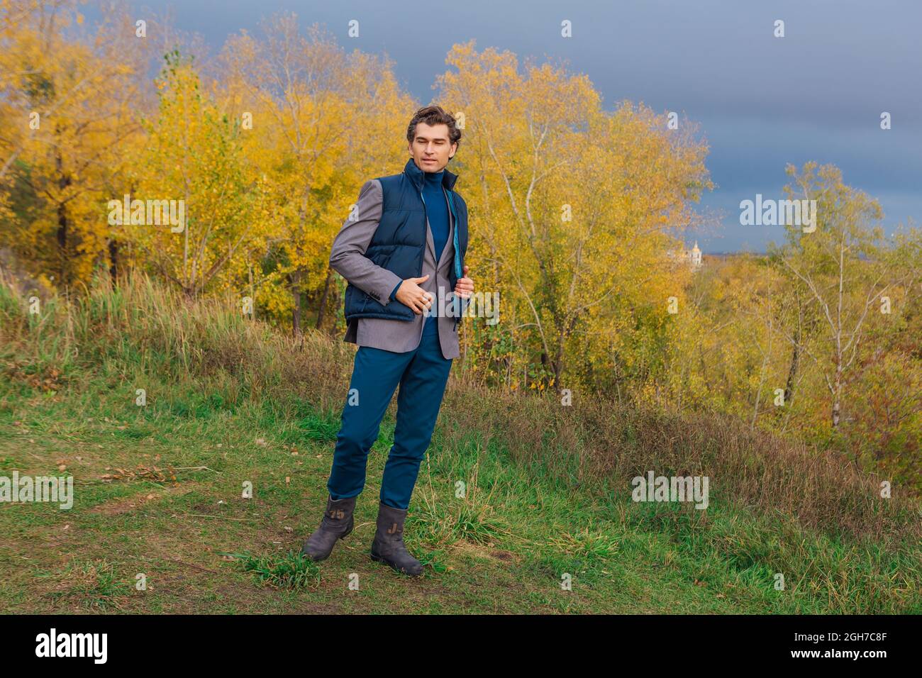 Tall handsome man walking outdoor in yellow autumn forest on the hill ...