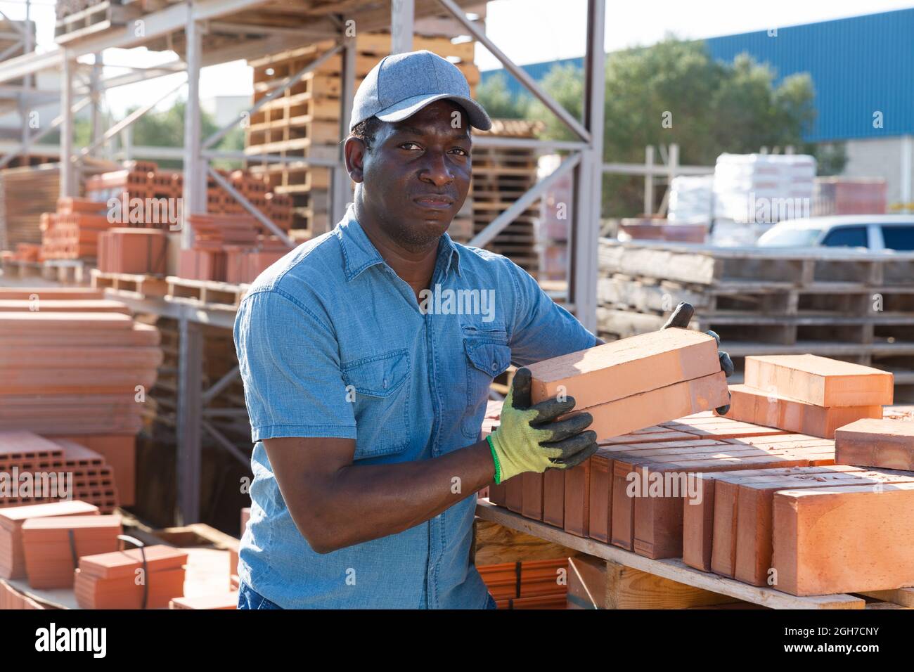 Male builder carrying bricks in outdoor warehouse Stock Photo - Alamy