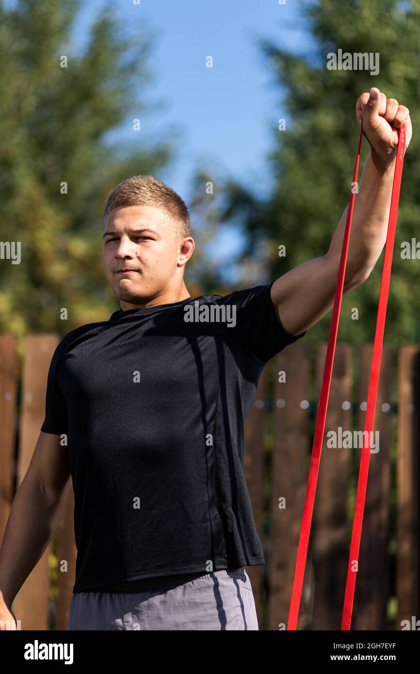 The young man goes in for sports at home in backyard in summer day ...