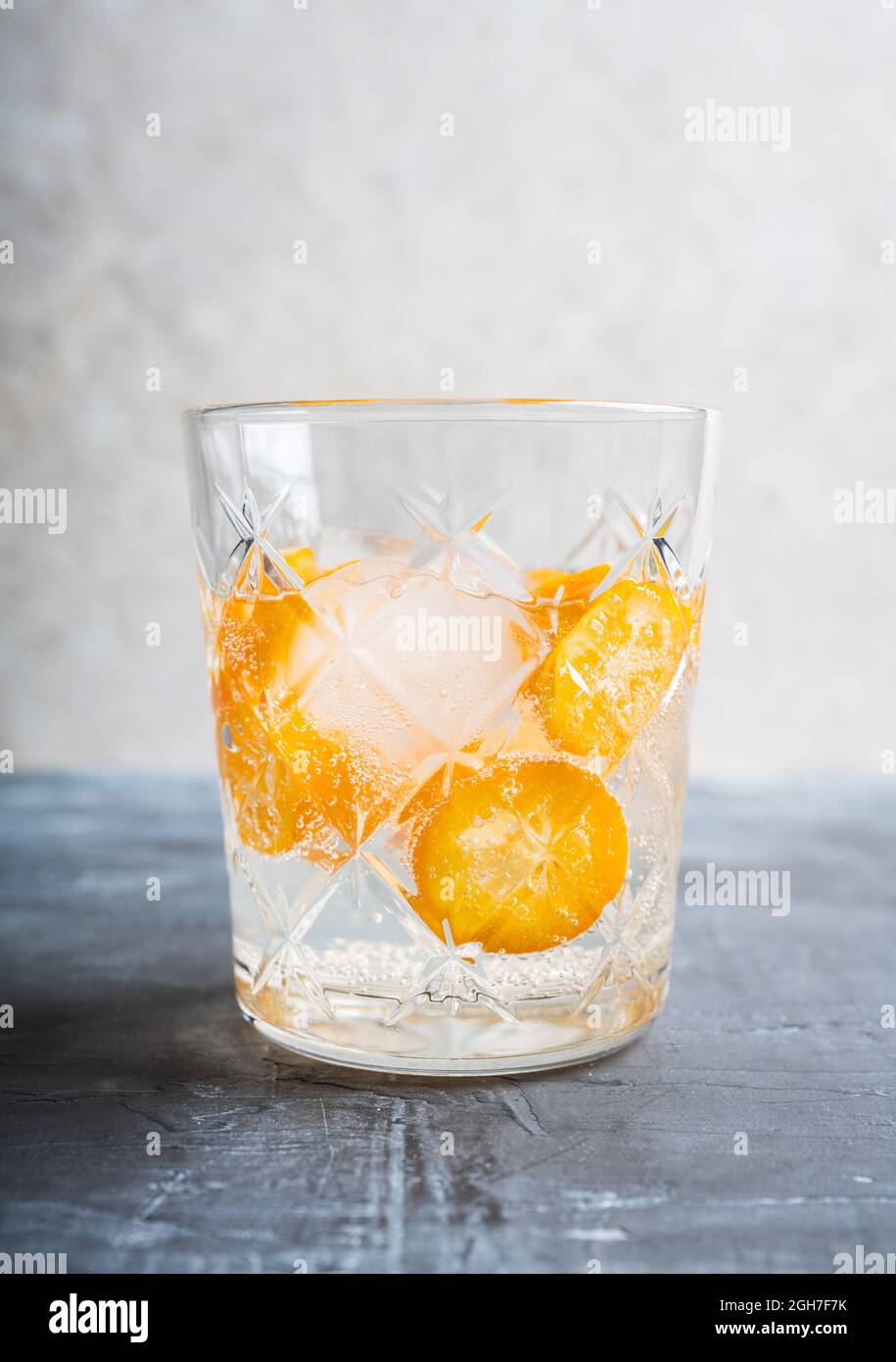 Old fashioned beverage with strong alcohol and kumquats on rustic ...