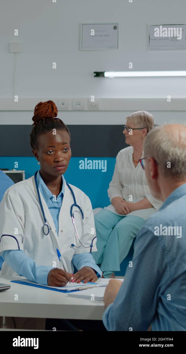 Young medical assistant giving x ray to doctor sitting at desk with ...