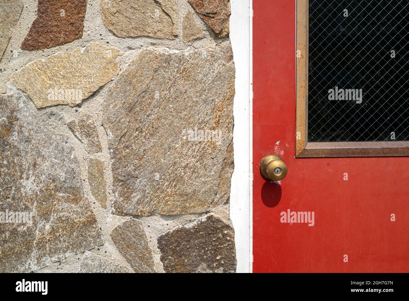 Detail of a red door and the rock siding of an old building Stock Photo ...