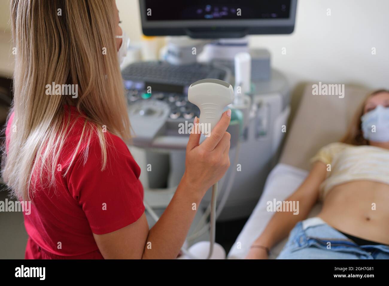 Female doctor holding ultrasound transducer in front of patient in ...
