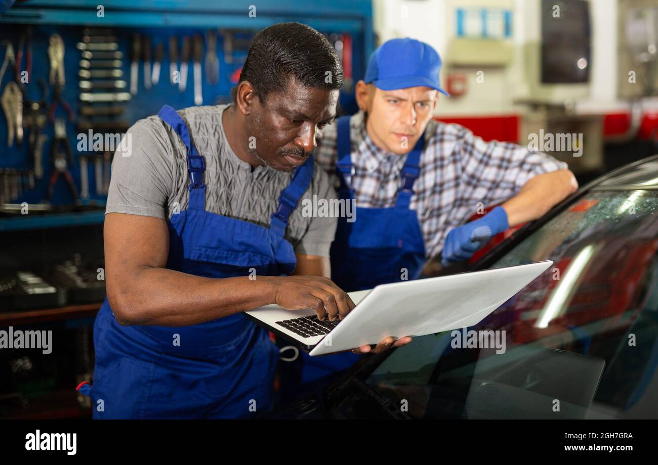 Mechanic and assistant working at service Stock Photo - Alamy