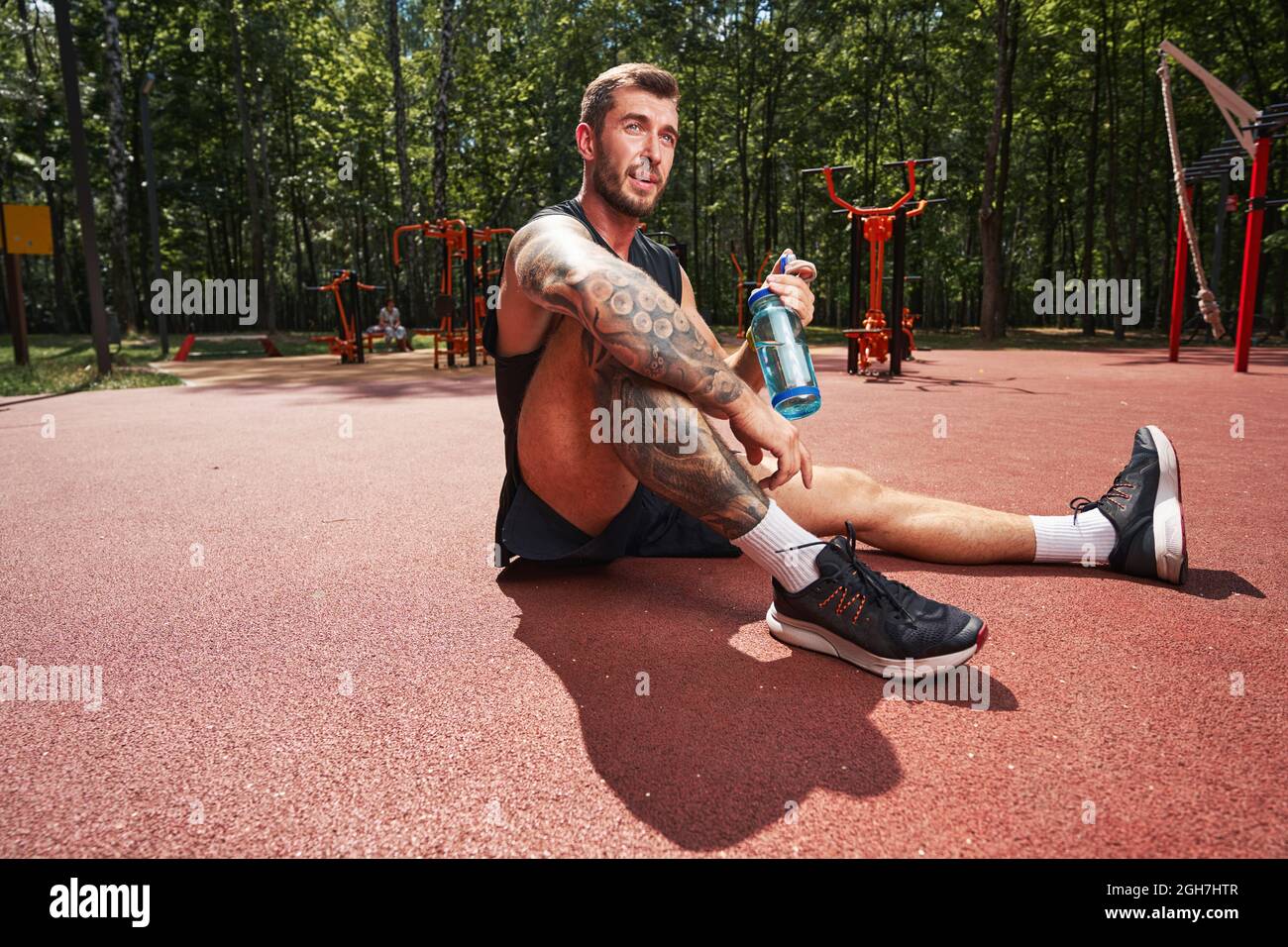 Happy muscular guy drinking water during workout outdoors Stock Photo ...
