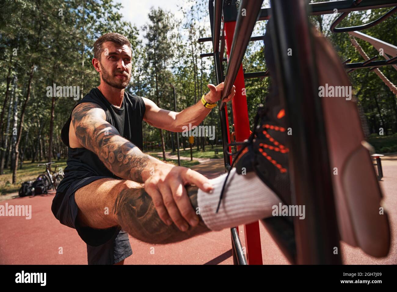 Young bearded bodybuilder doing stretching on sportsground Stock Photo ...