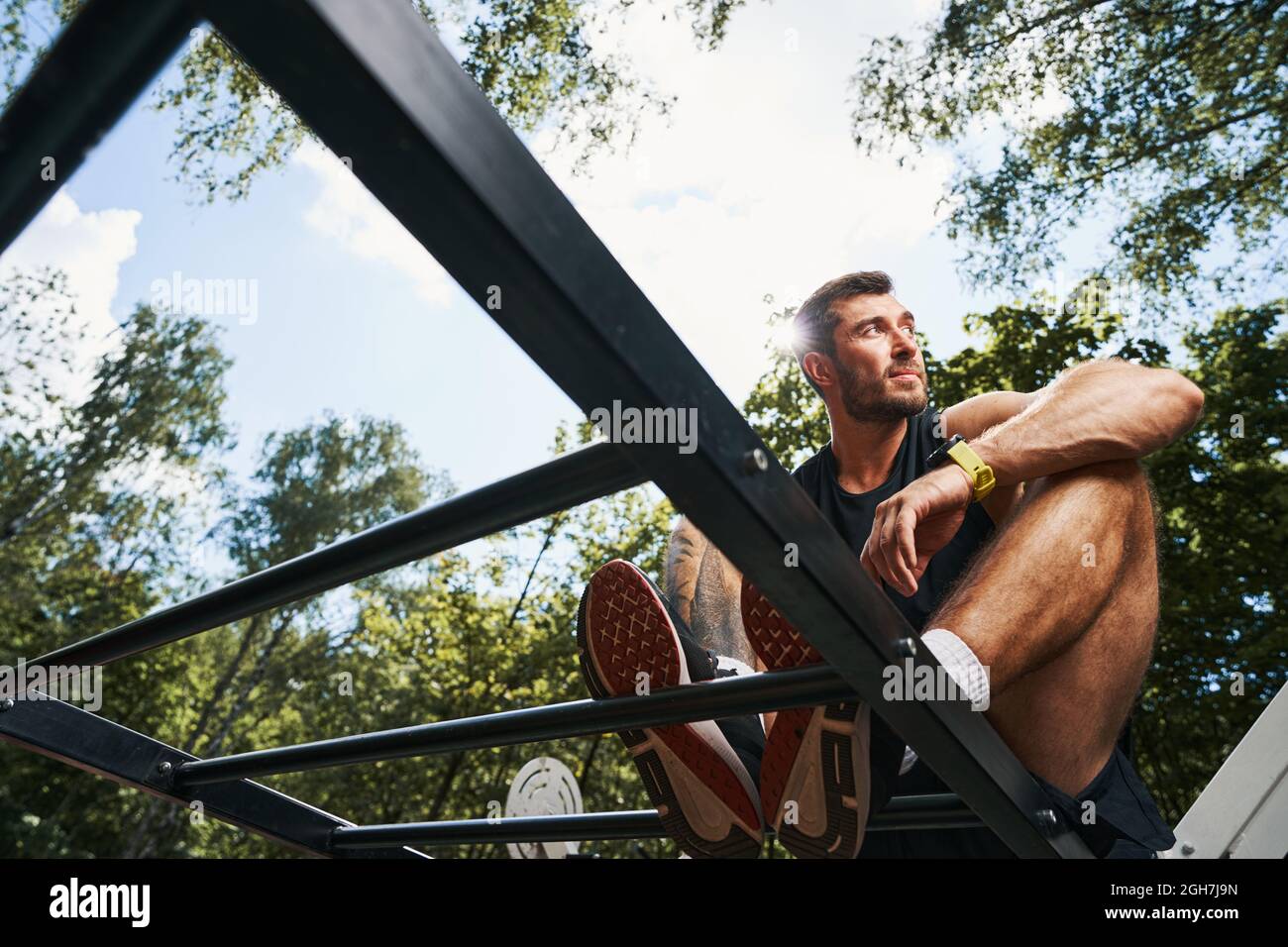 Low angle of smiling strong guy having rest after training on ...