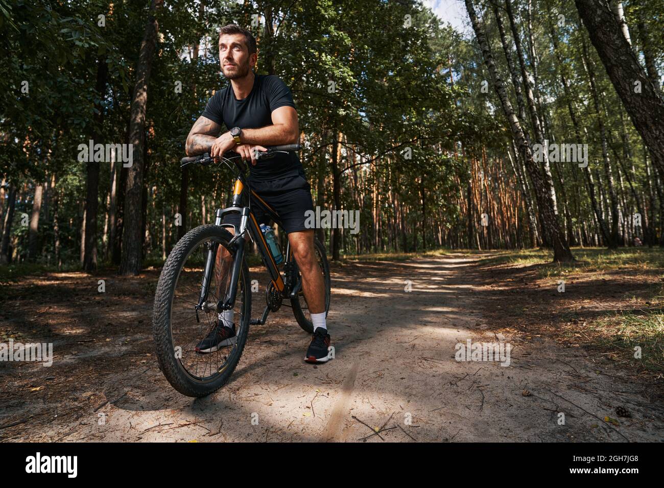 Low angle of cheerful athletic male relaxing in nature while riding ...