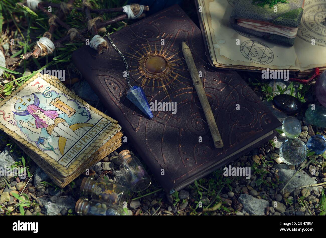 Magic book of spells, tarot cards and crystals on the grass in the ...