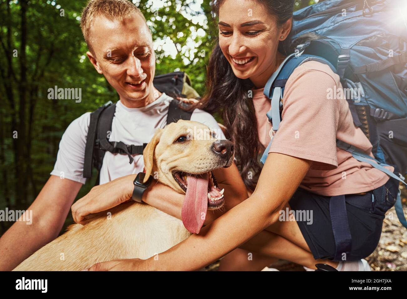 Happy active man and woman with backpacks are walking in nature and ...