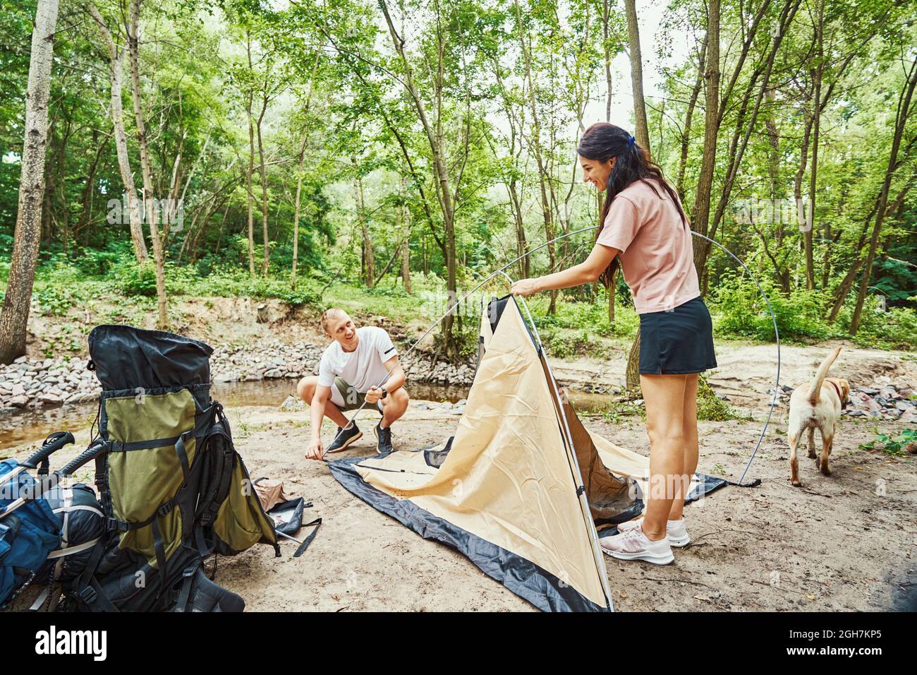 Happy young couple making camp in forest Stock Photo - Alamy