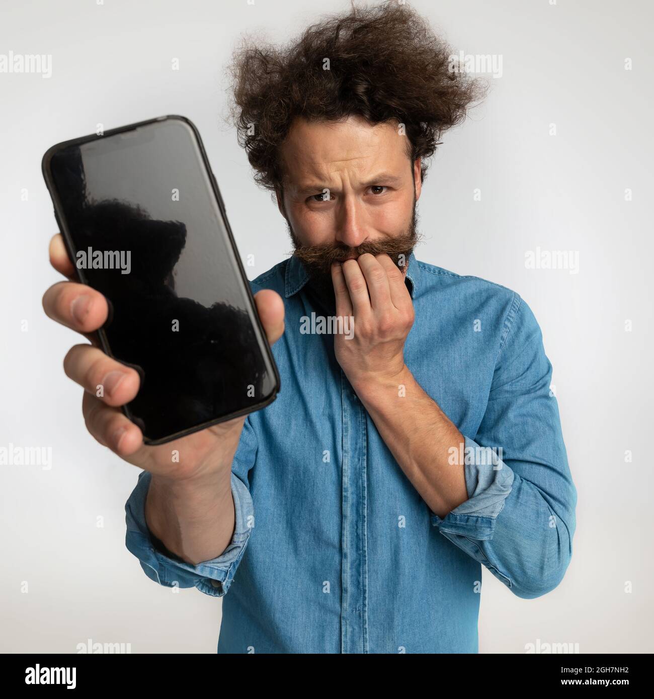 afraid young man in denim shirt being scared, biting fingers while ...