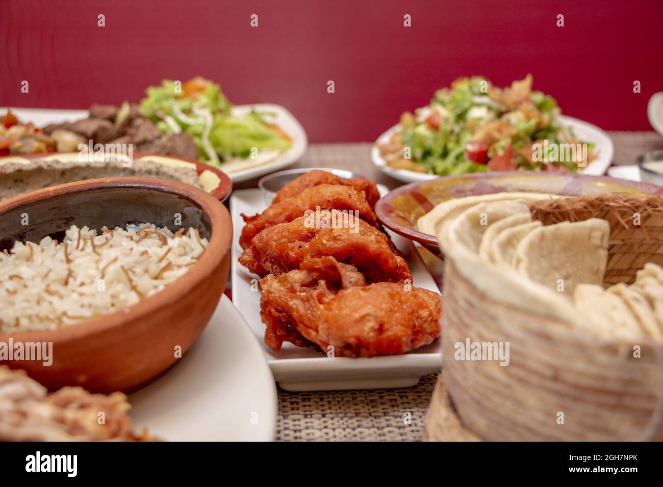 Close up of red sauce chicken, a bowl of rice, bread, and plates of ...