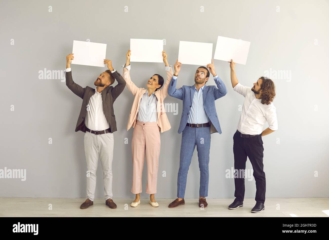 People holding blank white sheets of paper over their heads standing ...