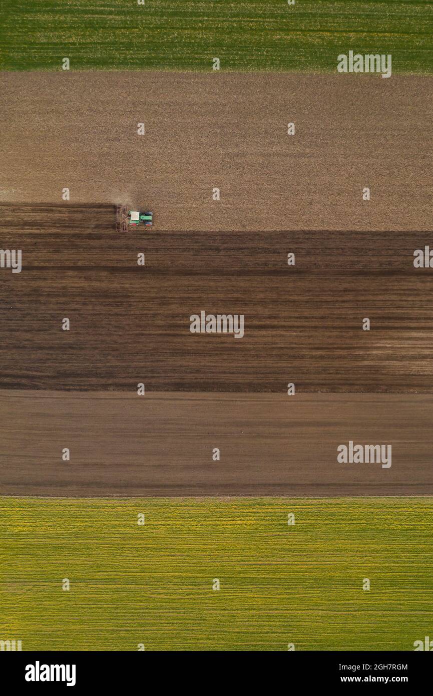 Aerial view of agricultural tractor tilling and harrowing ploughed ...
