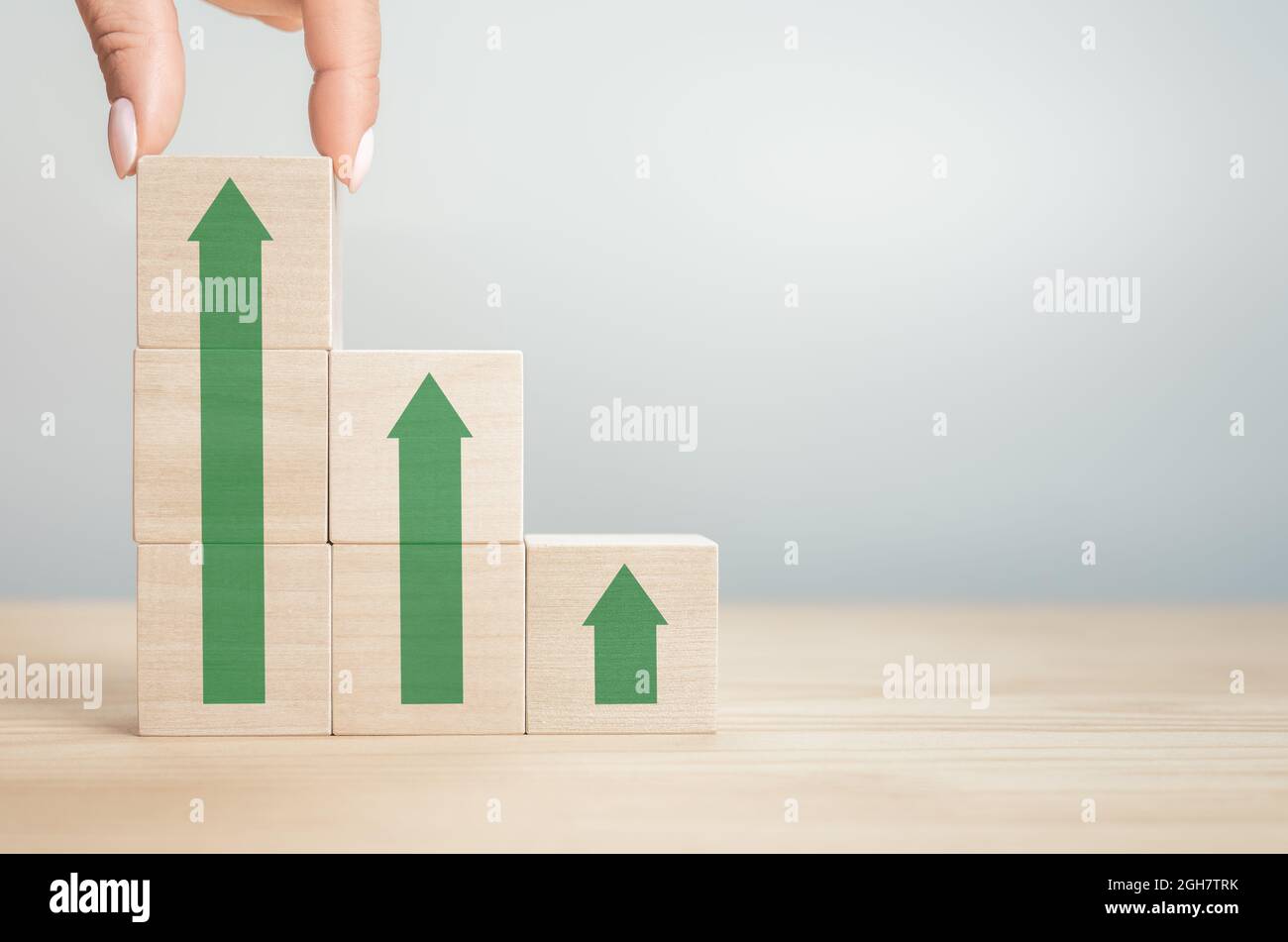Hand arranging wood block stacking as step stair with green arrow up ...