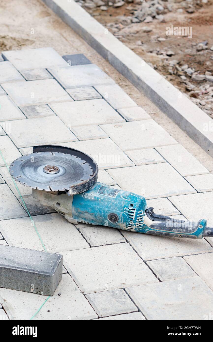 Worn-out electric angle grinder with diamond cut-off wheel at a paving ...