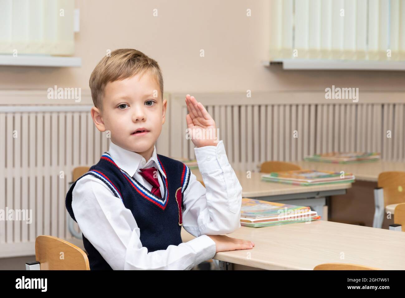 A first-grader boy at a desk with textbooks and notebooks in the ...