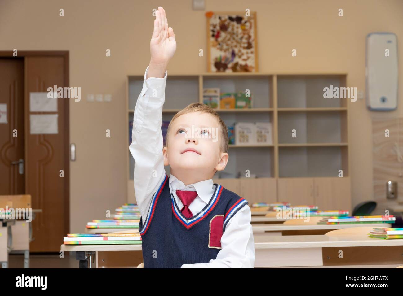 A first-grader boy at a desk with textbooks and notebooks in the ...