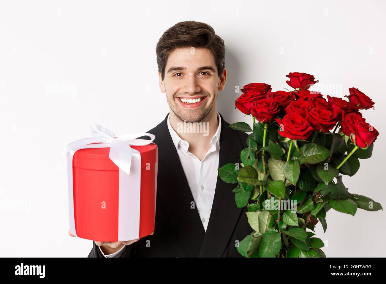 Close-up of handsome bearded man in suit, holding present and bouquet ...