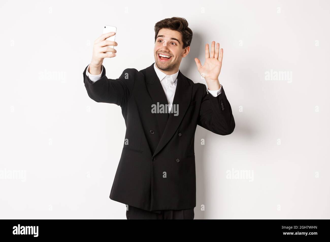 Image of handsome man in suit, having video call and waving hand at ...